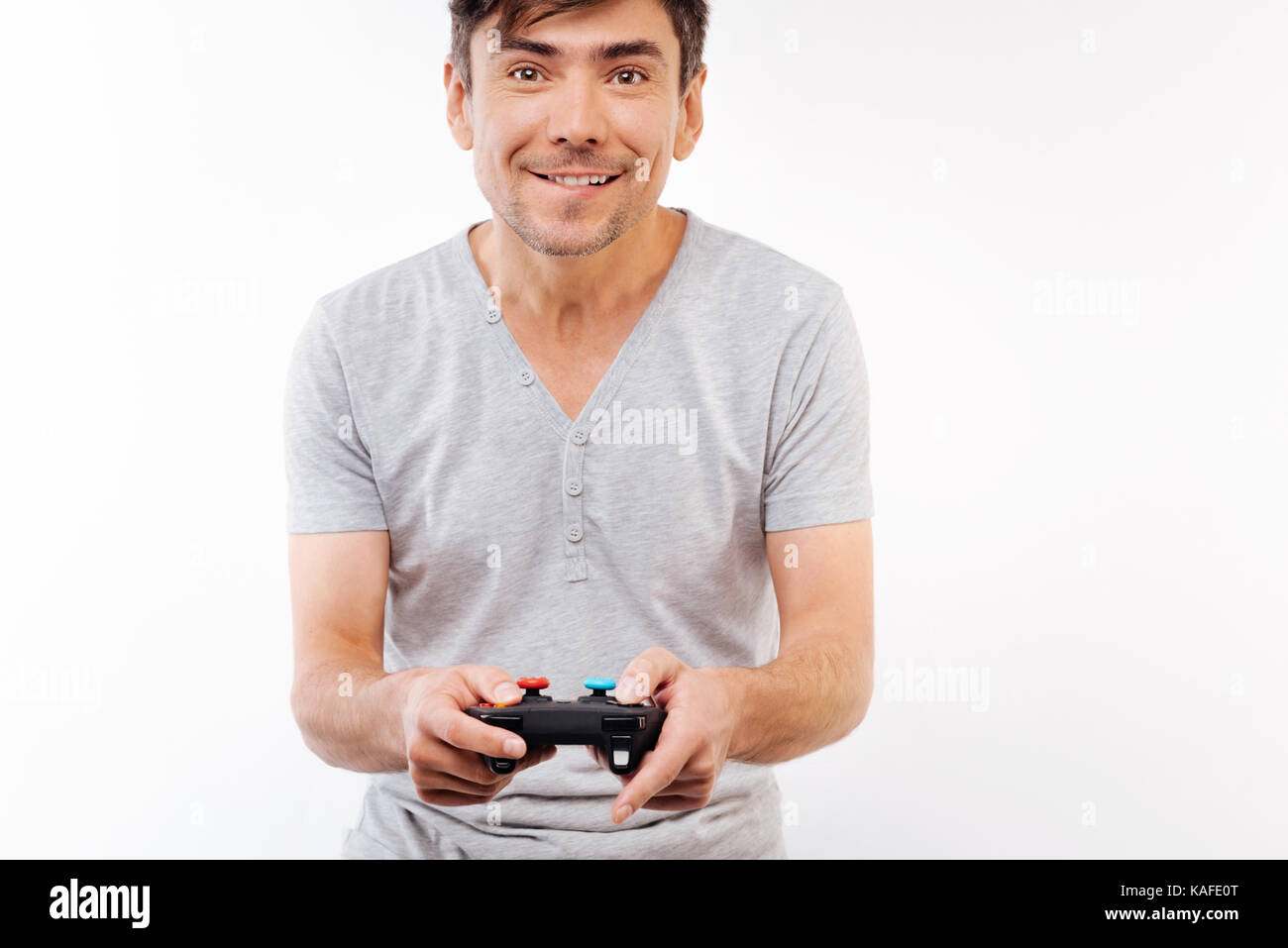 Upbeat young man holding video game controller Stock Photo - Alamy
