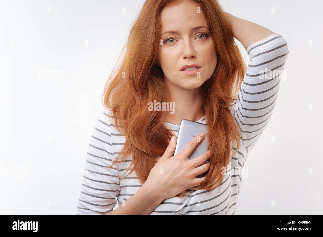 Upset ginger-haired woman pressing phone to her chest Stock Photo - Alamy