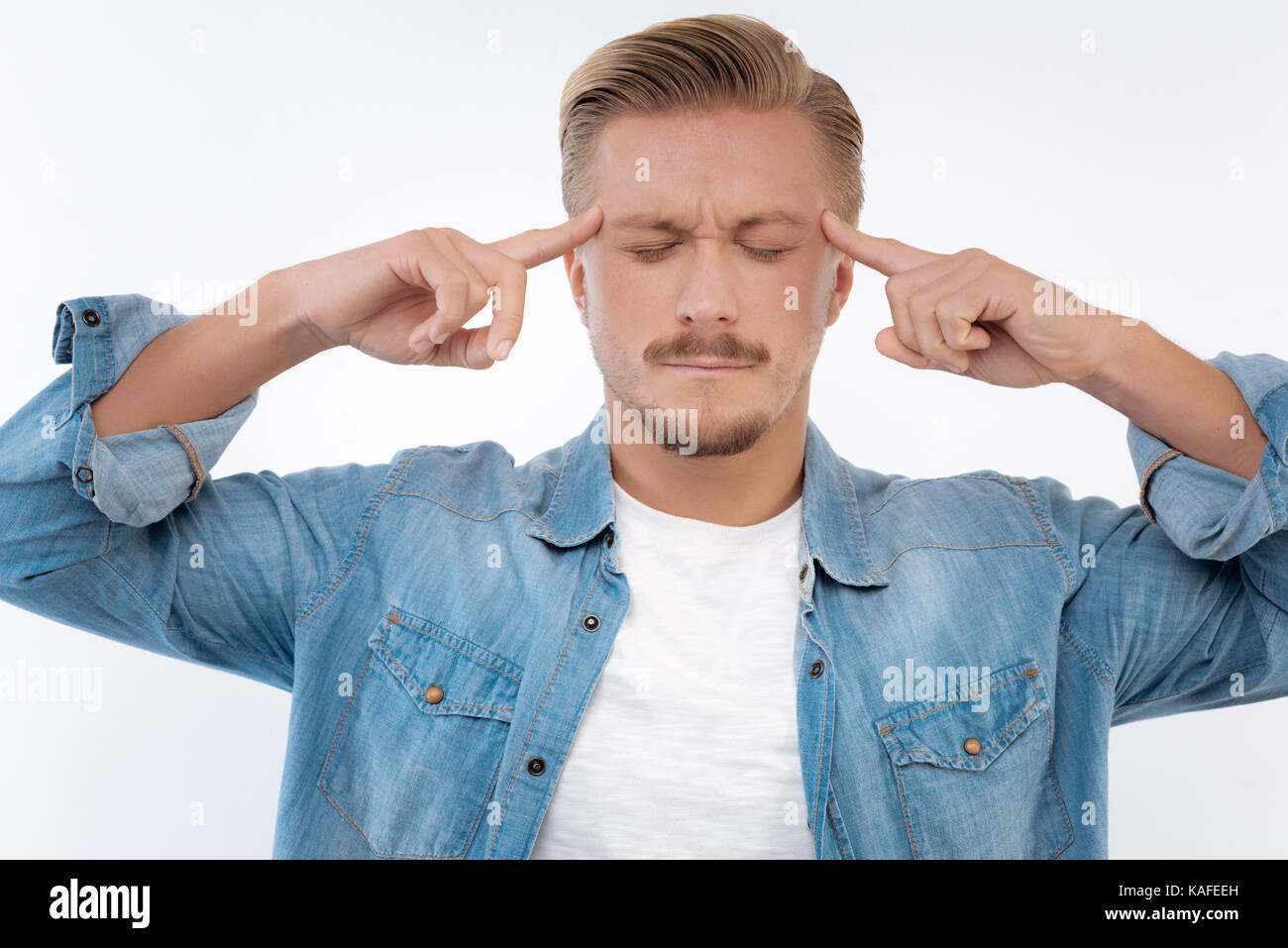 Young man pressing fingers to his temples Stock Photo - Alamy