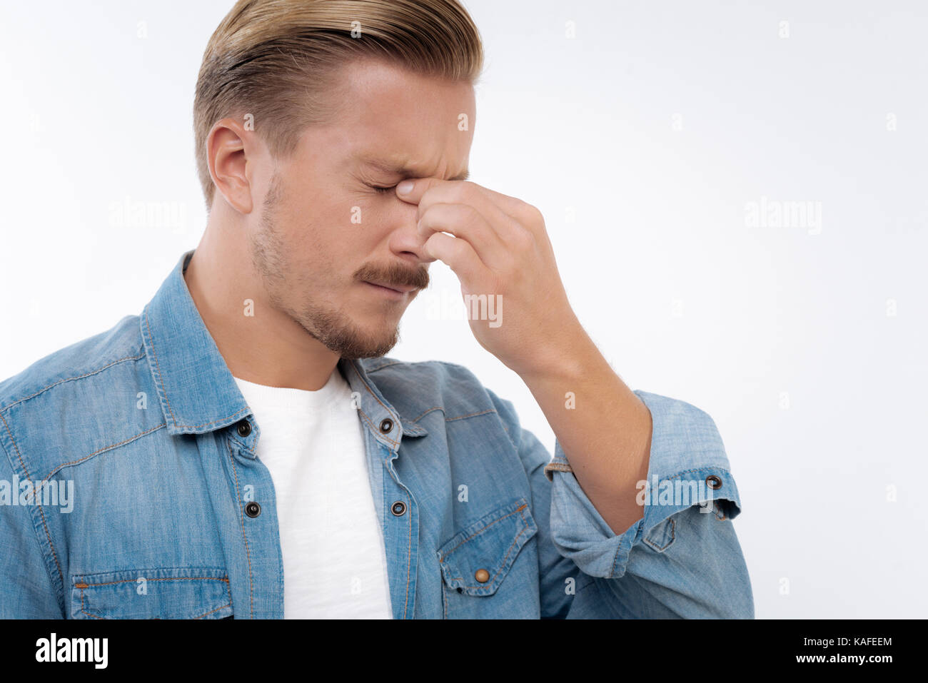 Tired man pinching bridge of his nose Stock Photo - Alamy