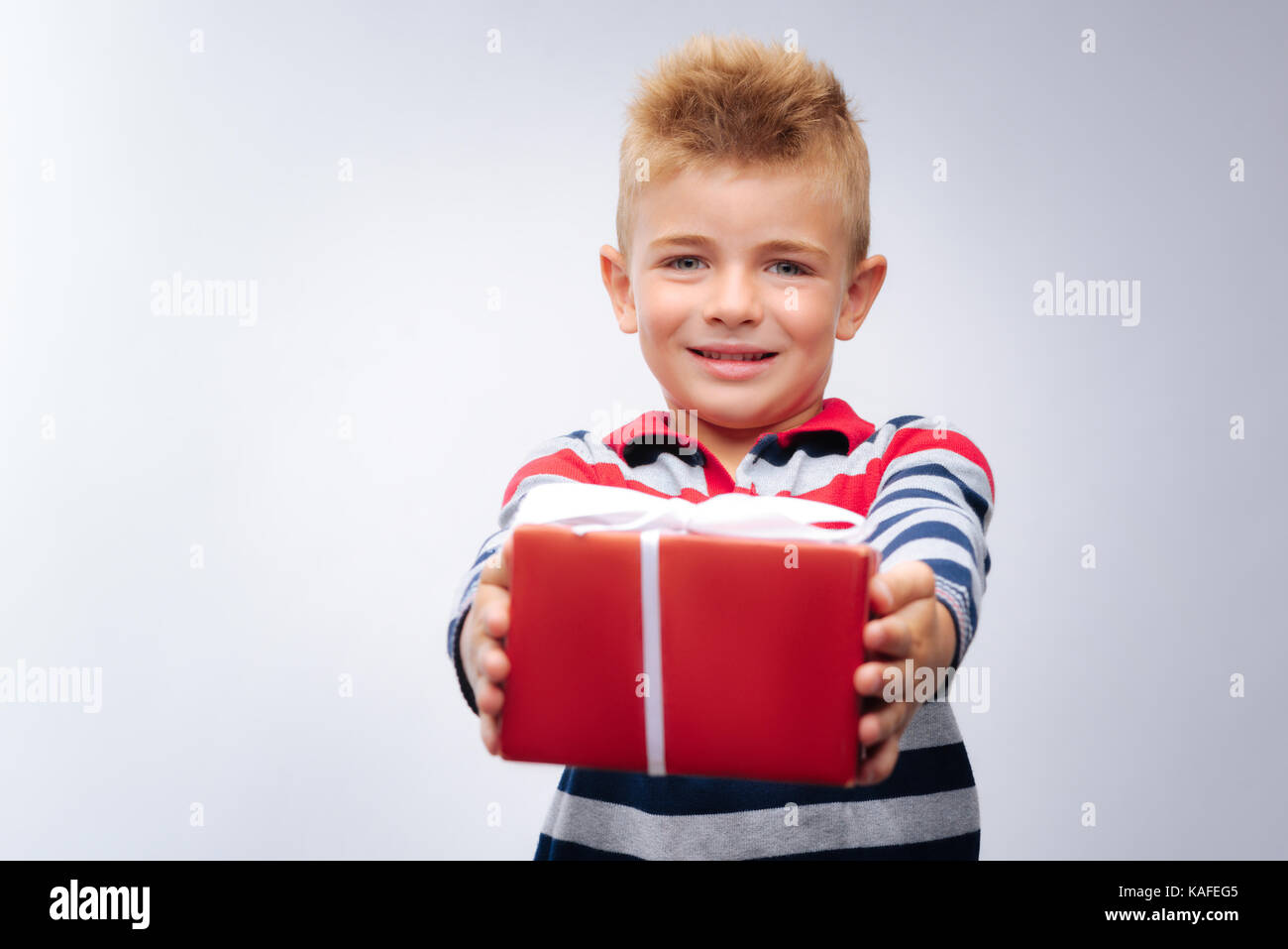 Cute little boy holding a red box with gift Stock Photo - Alamy