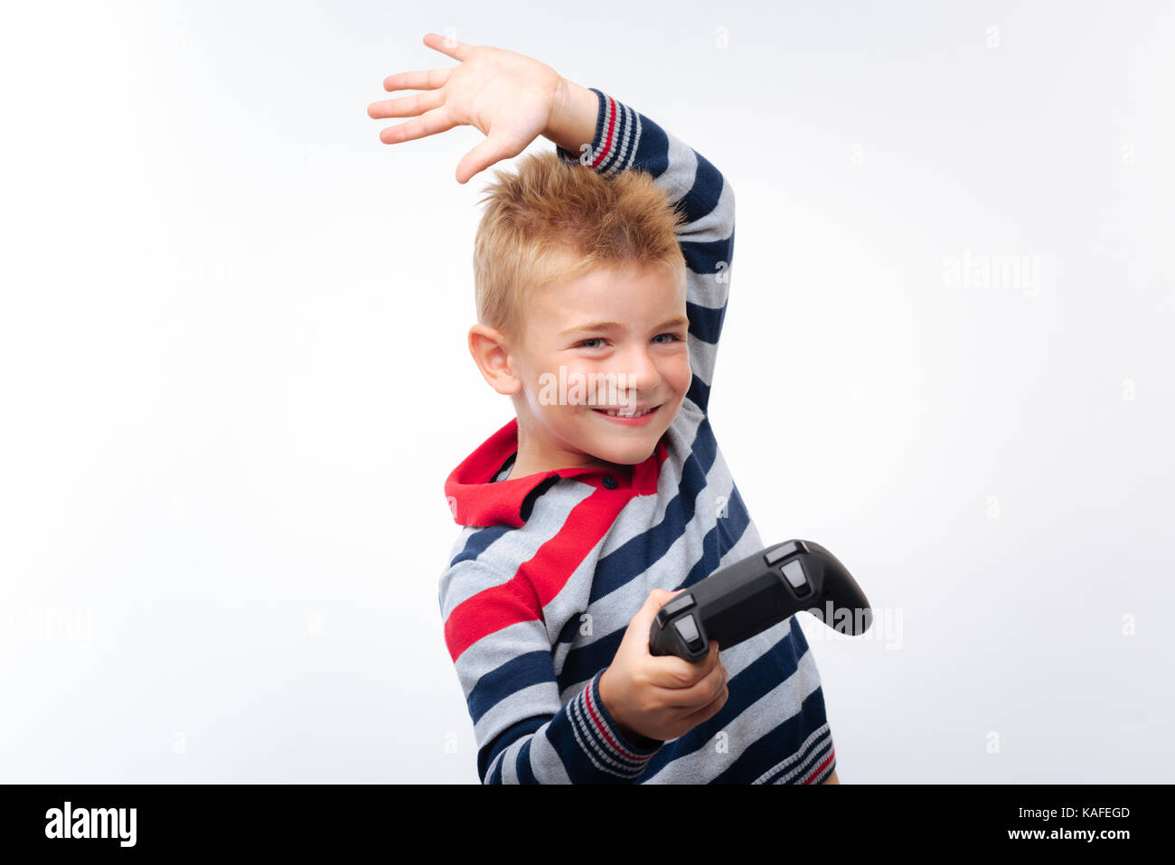 Little boy raising hand and holding game controller Stock Photo - Alamy
