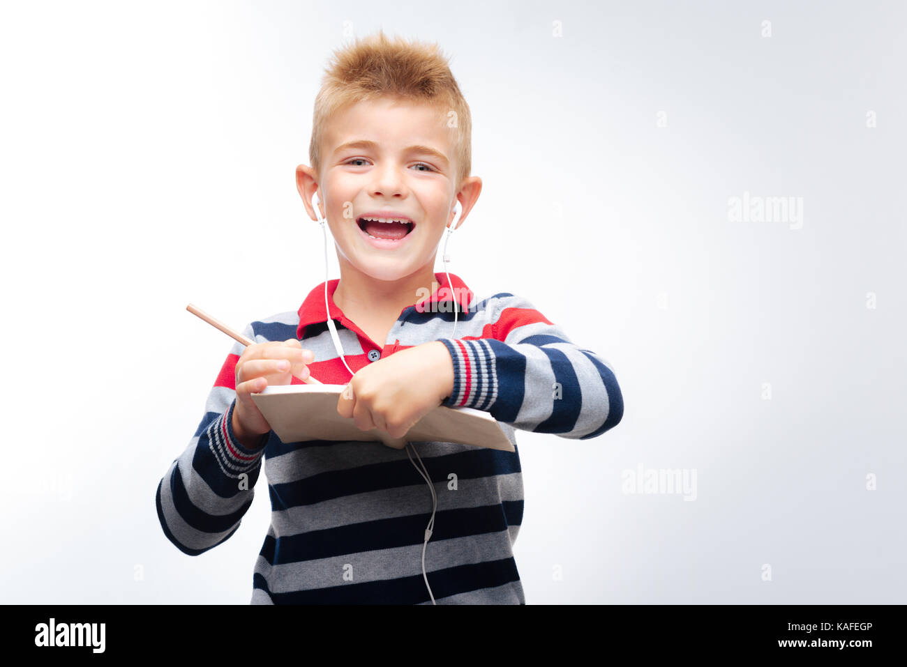 Little boy making notes while listening to music Stock Photo - Alamy