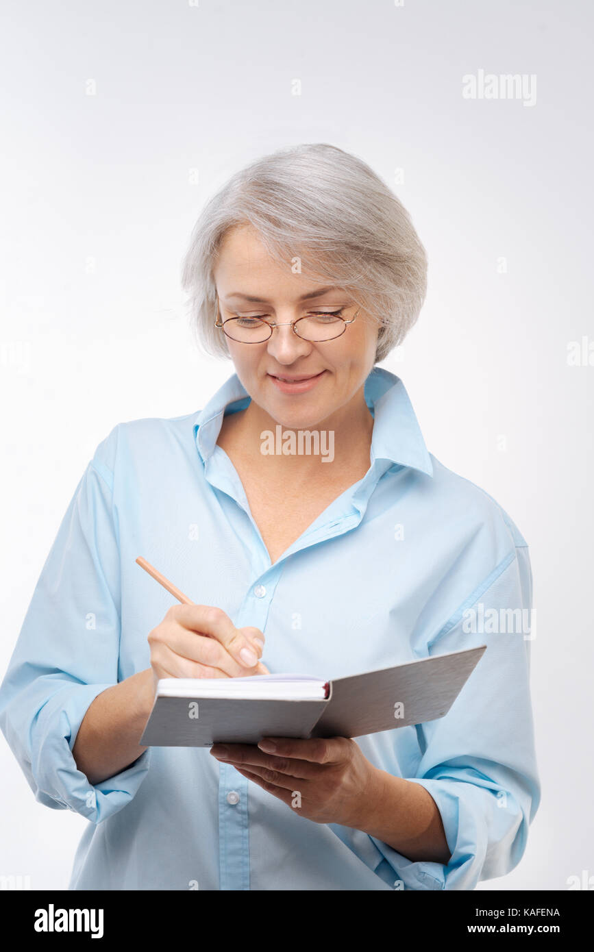 Beautiful grey-haired woman writing in notebook Stock Photo - Alamy