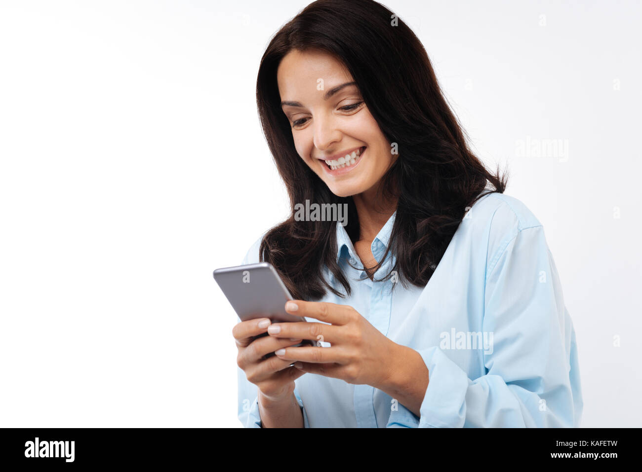 Cheerful dark-haired woman sending text message Stock Photo - Alamy