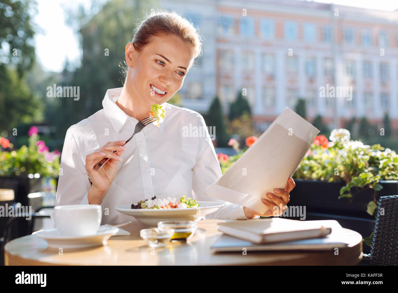 Beautiful woman reading documents while eating out Stock Photo - Alamy