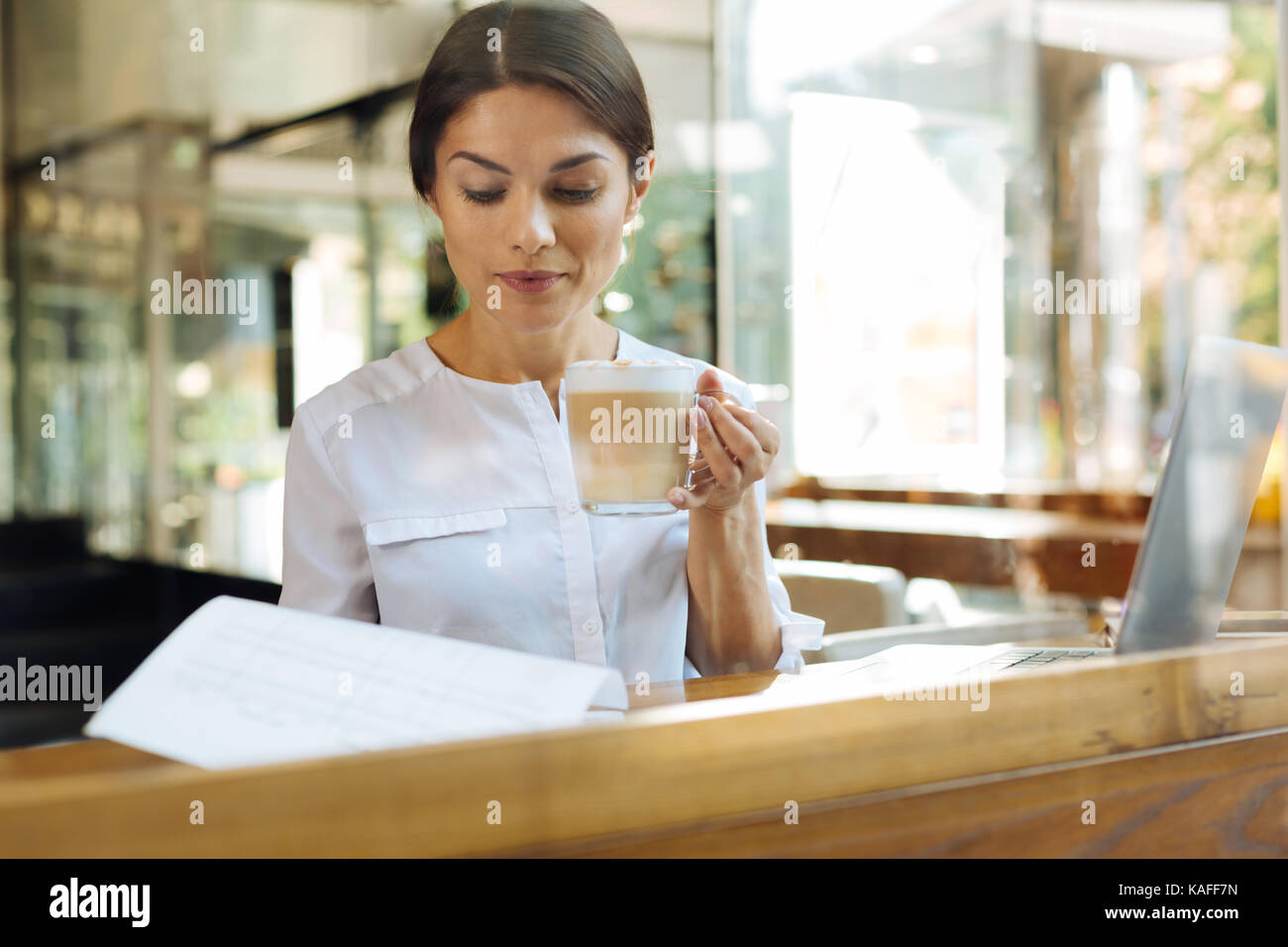 Young woman reading contract while drinking latte Stock Photo - Alamy