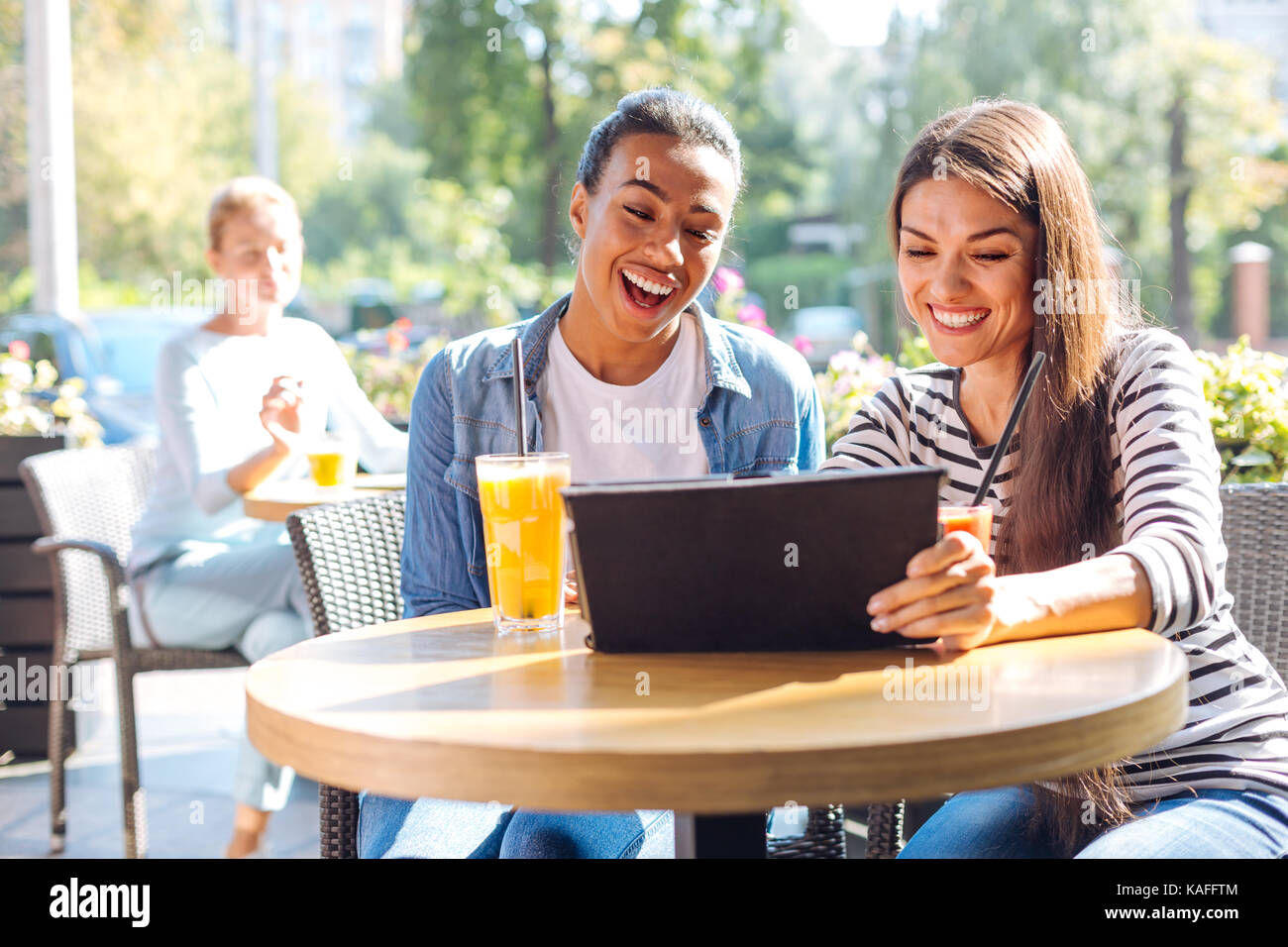 Happy women laughing while watching video in cafe Stock Photo - Alamy