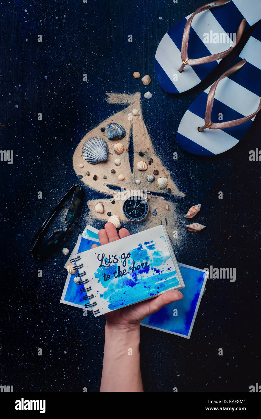 Sailboat silhouette made from sand and seashells, a notebook in a ...
