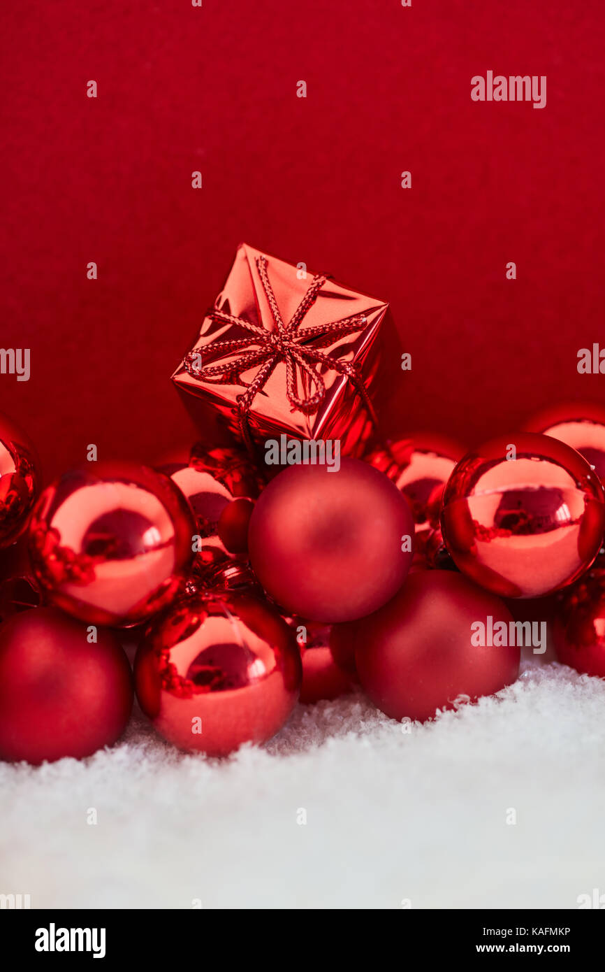Small christmas present on red baubles as background Stock Photo - Alamy