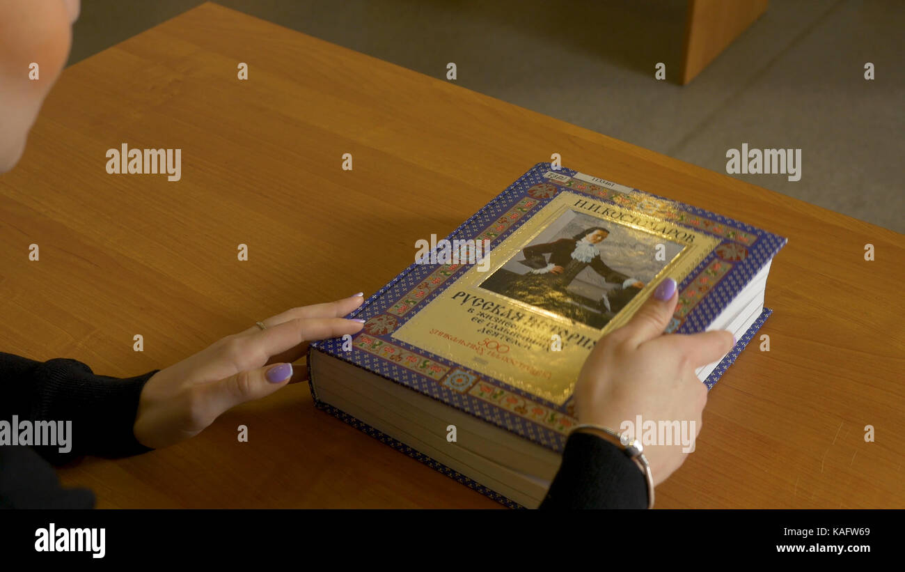 Woman sitting reading on the table. Woman closes the book after reading ...