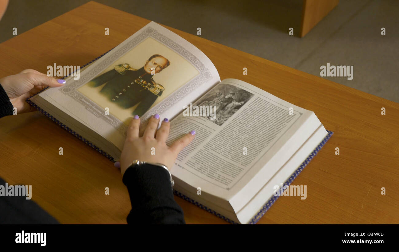 Woman sitting reading on the table. Woman closes the book after reading ...