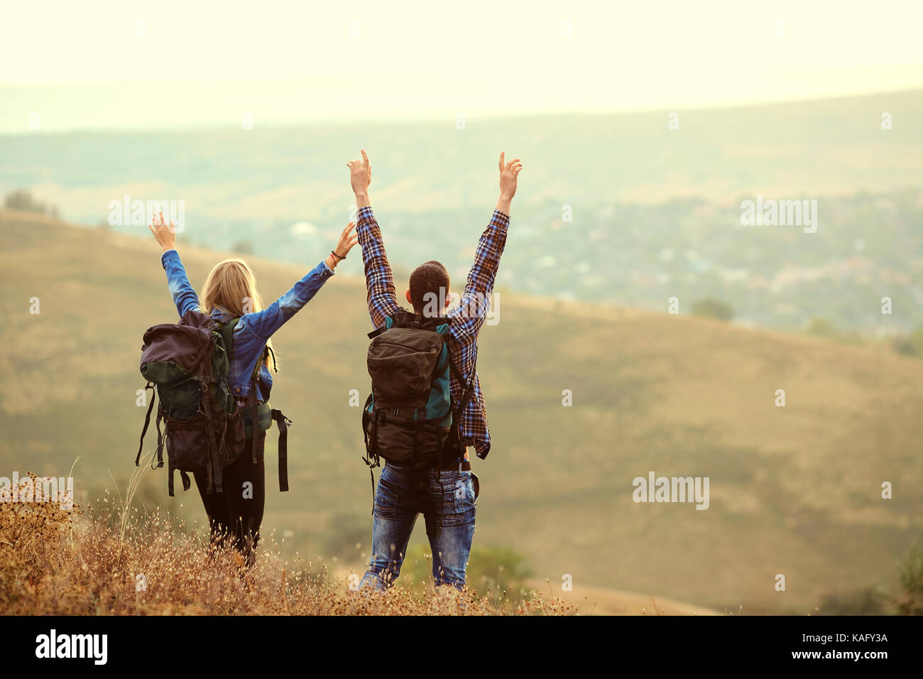 A couple of tourists with backpacks raised their hands up in nat Stock ...