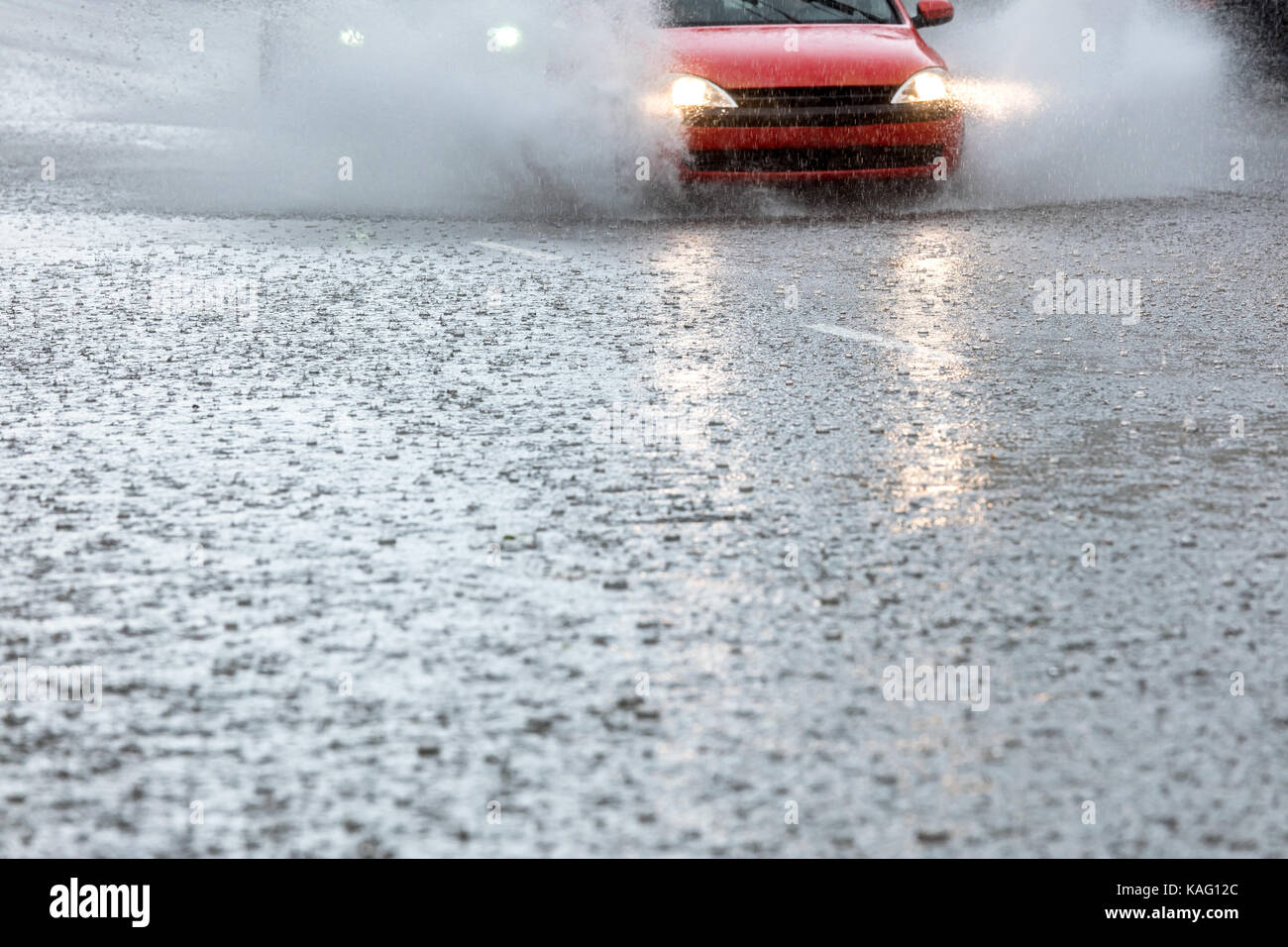 car driving on flooded city road with water spraying from the wheels ...