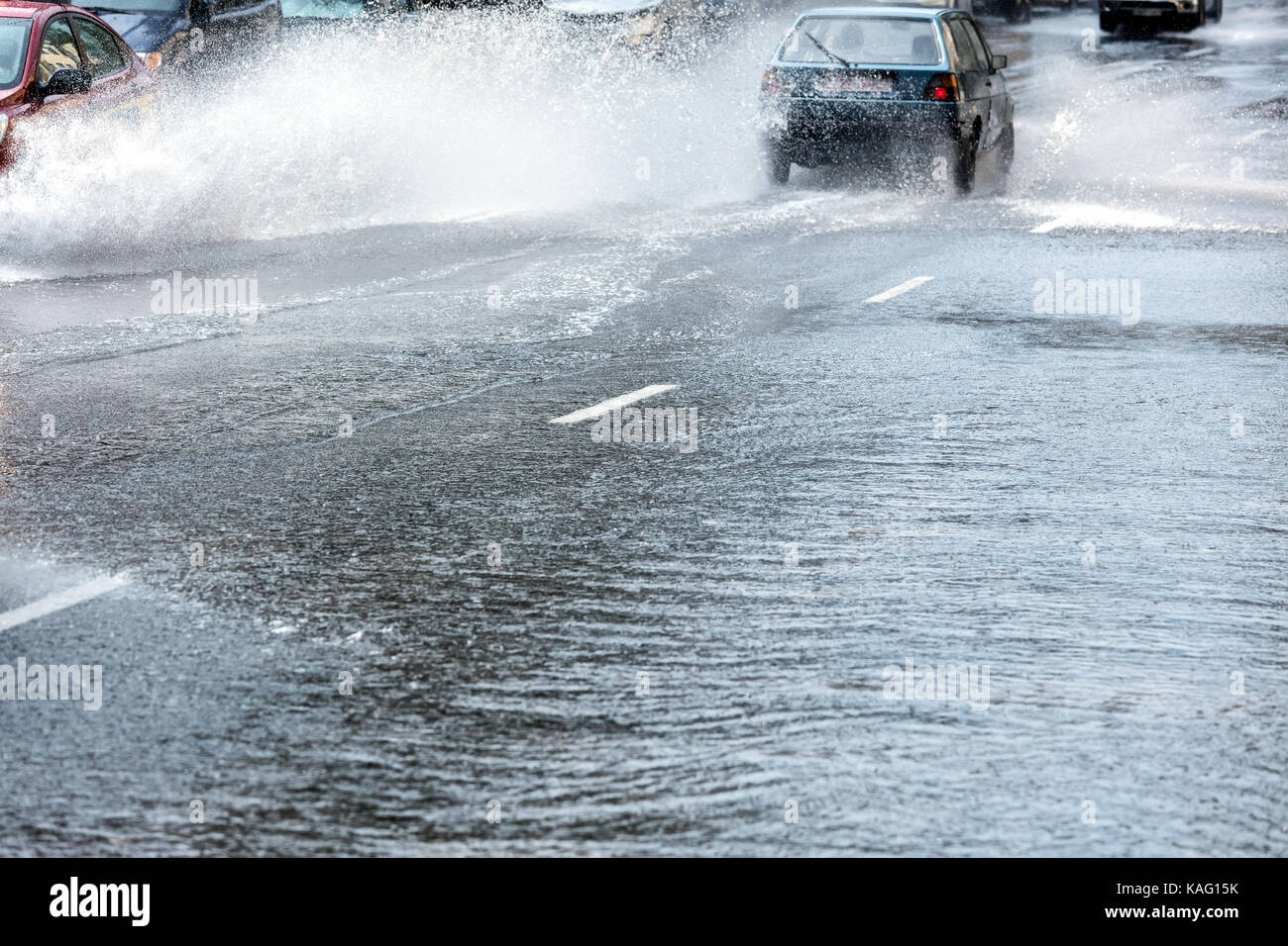 flooded city road during heavy rain. water splashing from car wheels ...