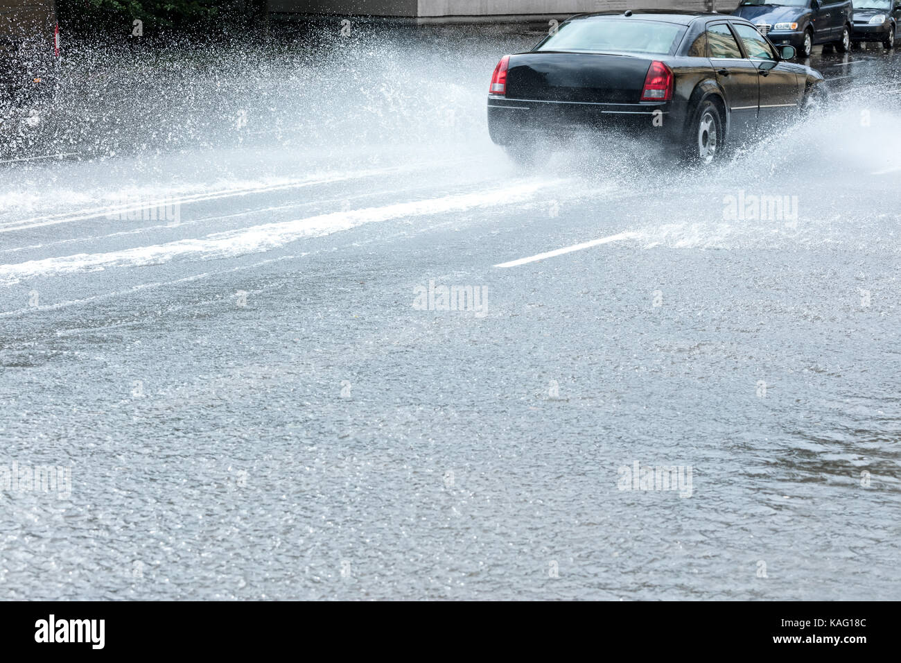 car driving through water puddles on flooded city road Stock Photo - Alamy