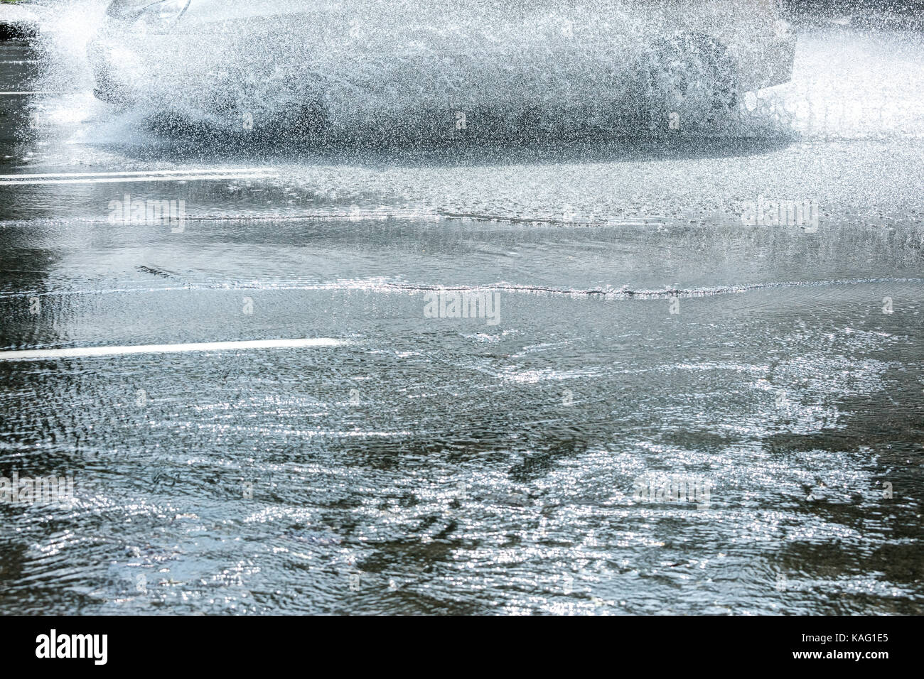 rainwater splashing from wheels of car in motion on flooded road Stock ...