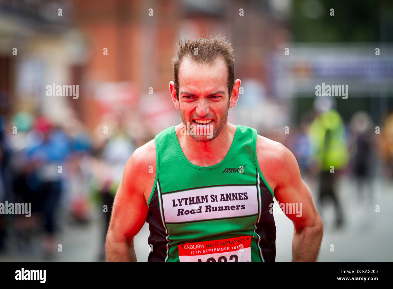 Male runner grimacing as he approaches the finish line in the English ...
