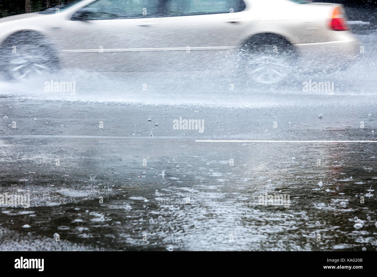 car driving on city road on fast speed creating water splashes Stock ...