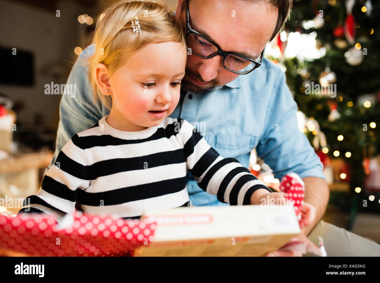 Little girl with her father opening Christmas present Stock Photo - Alamy