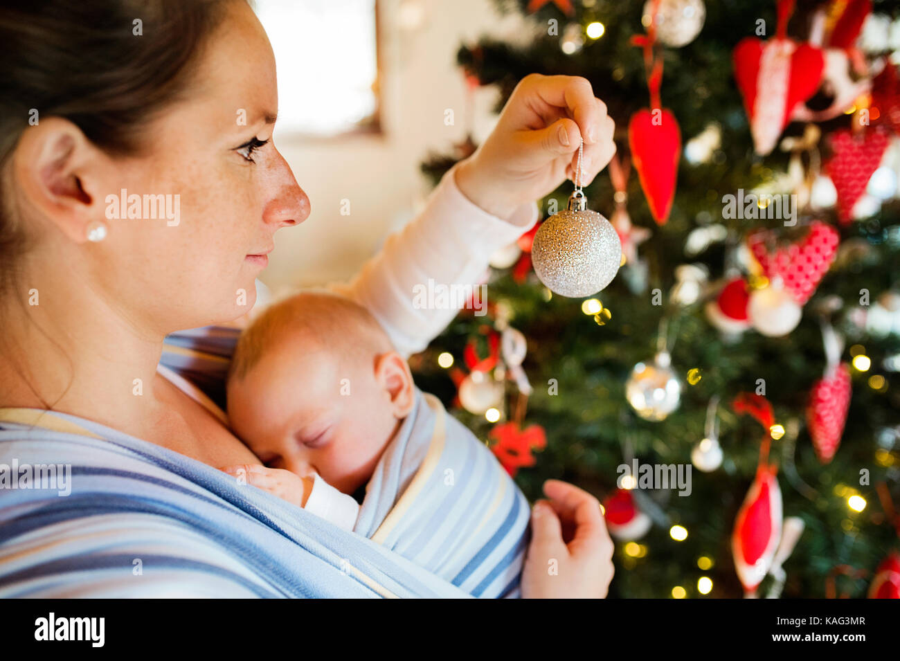 Young woman with a baby decorating Christmas tree Stock Photo - Alamy