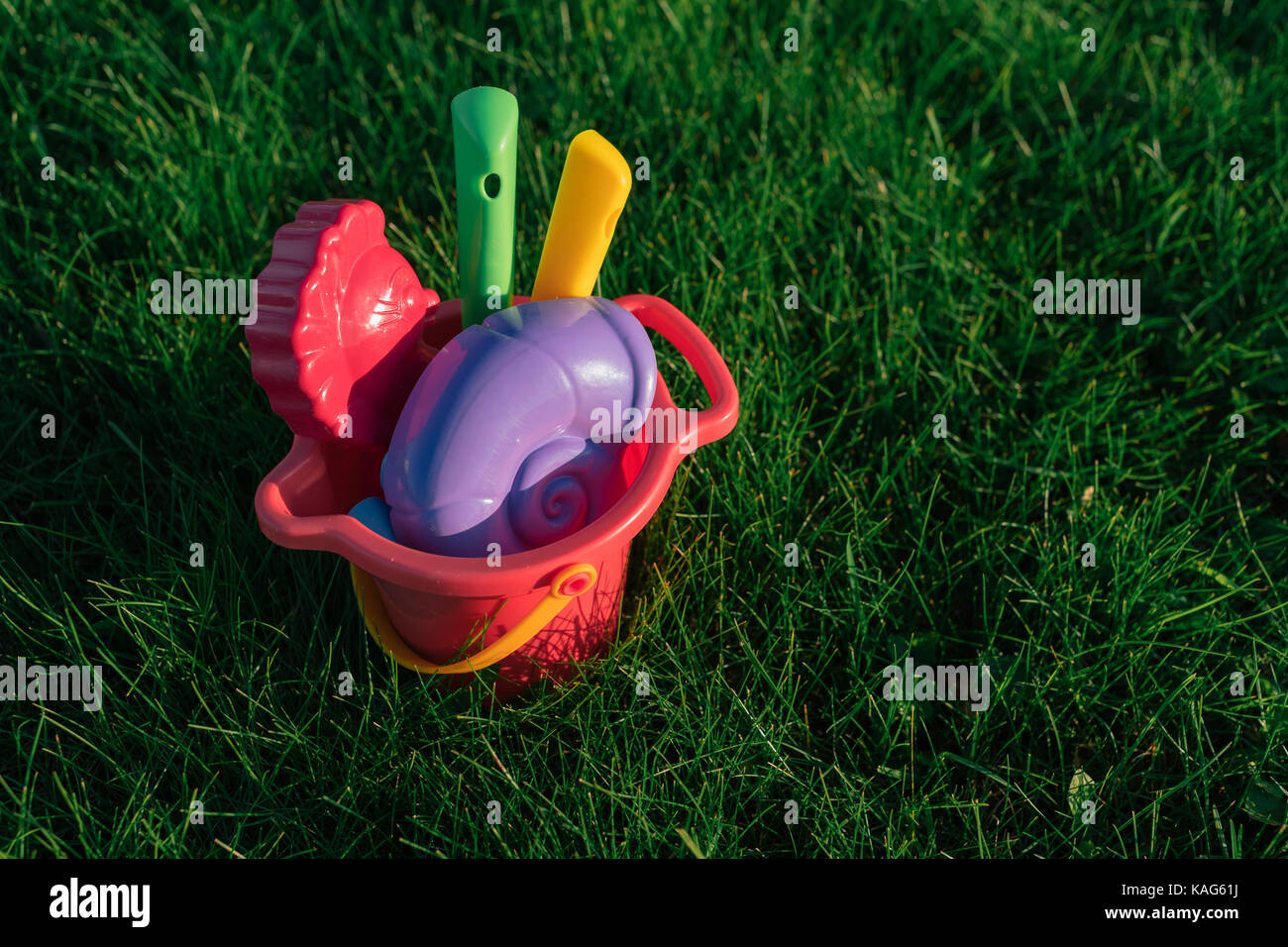 children's colorful toys in a bucket on a green lawn Stock Photo - Alamy