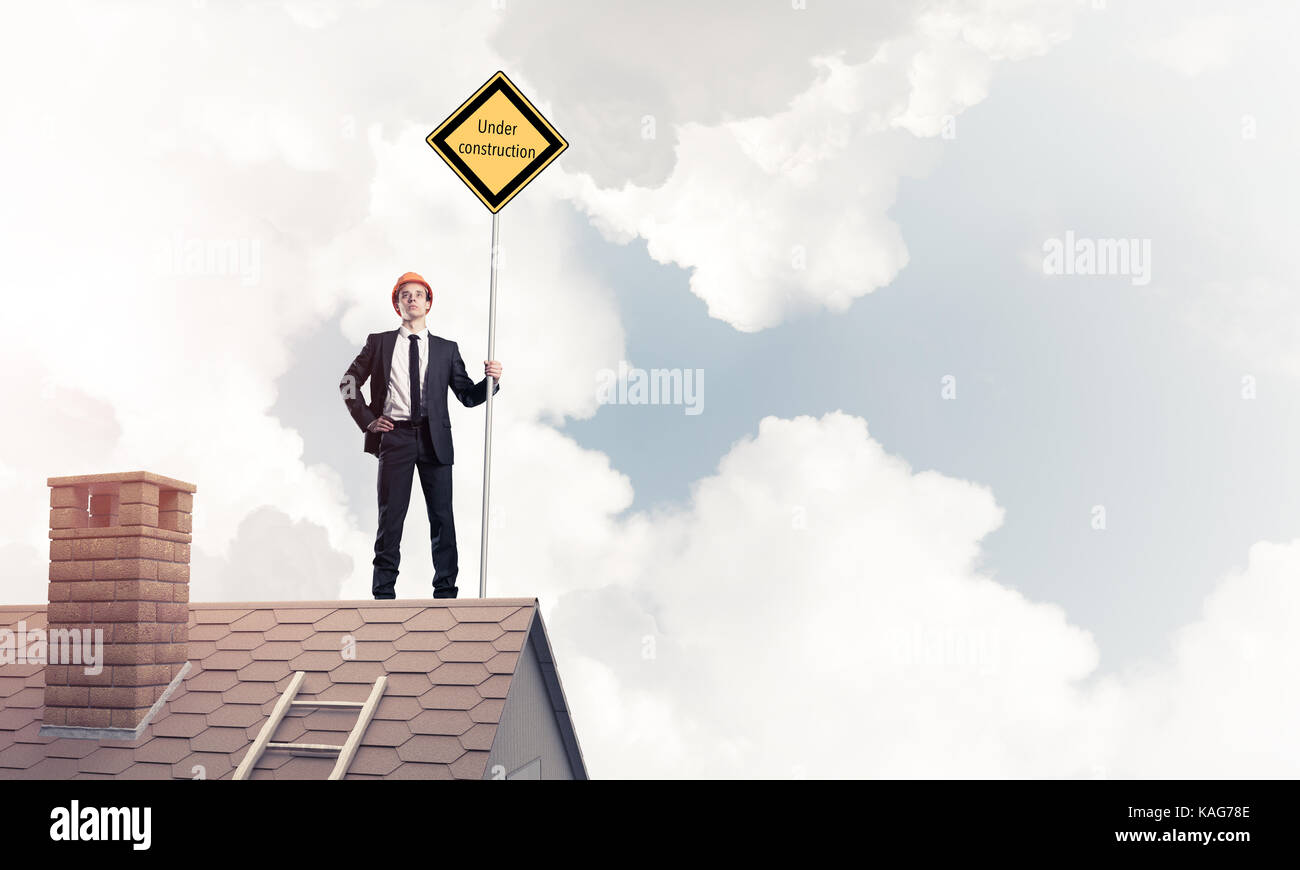 Young businessman on house brick roof holding yellow signboard Stock ...
