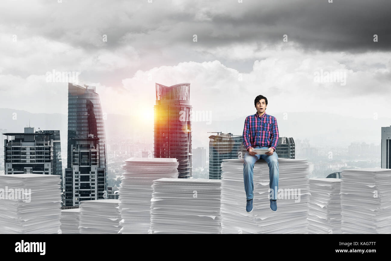 Attractive man sitting on pile of paper documents Stock Photo - Alamy