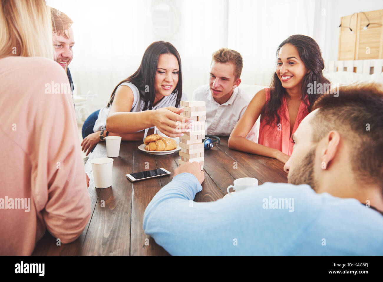 Group of creative friends sitting at wooden table. People having fun ...