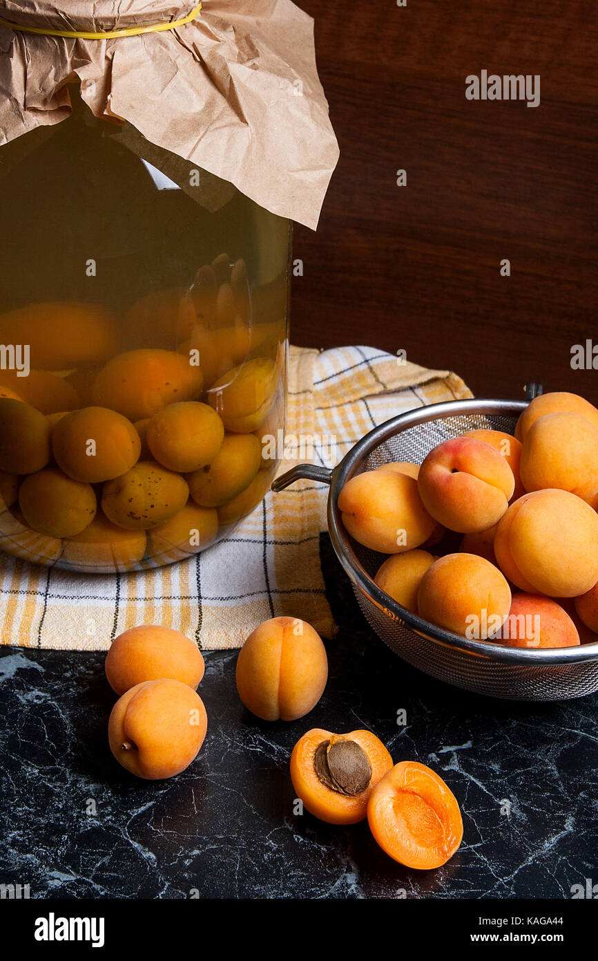 Ripe organic apricots harvested at summer time and big glass jar with ...