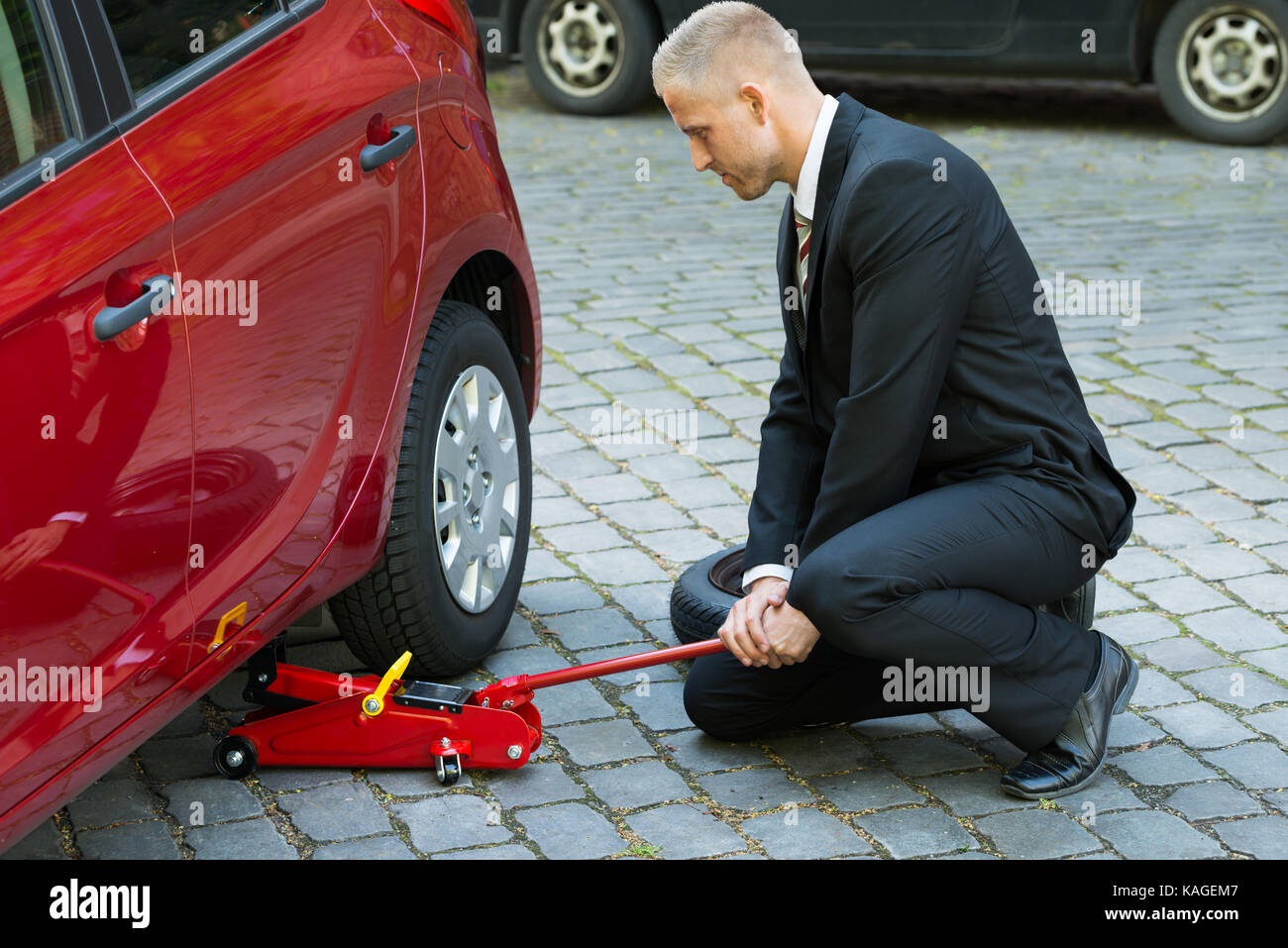 Man Trying To Lift The Car With Red Hydraulic Floor Jack For Repairing ...