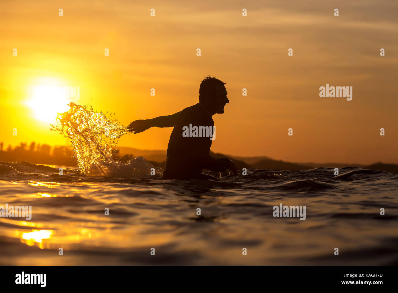 Surfer waiting in the line up for a wave at sunrise or sunset Stock ...