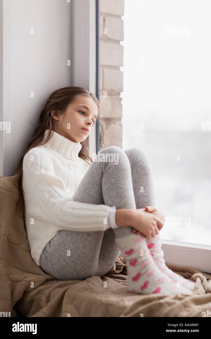 sad girl sitting on sill at home window in winter Stock Photo - Alamy