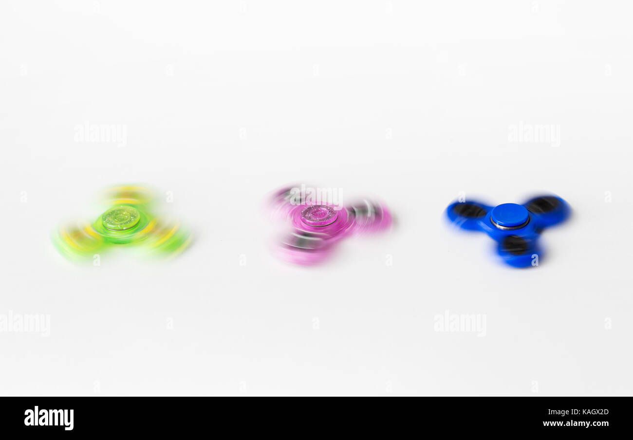 three spinning fidget spinners on white background Stock Photo - Alamy