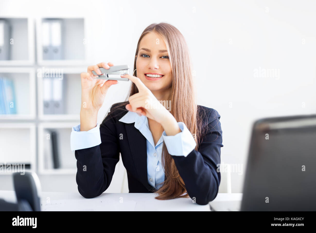 smiling young business woman put a finger in a stapler in office Stock ...