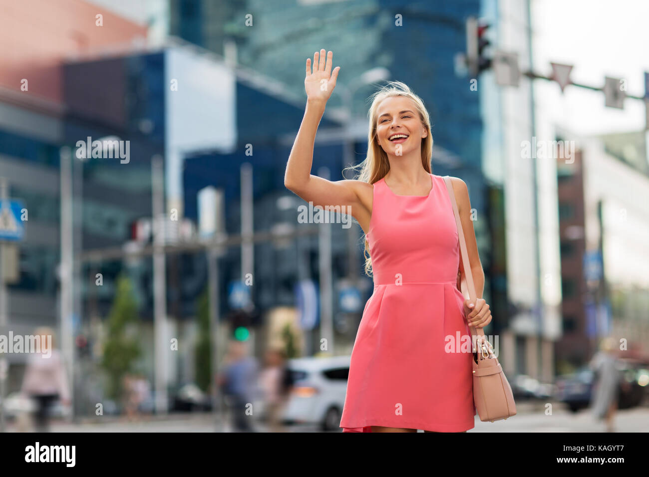 happy young woman waving hand on city street Stock Photo - Alamy