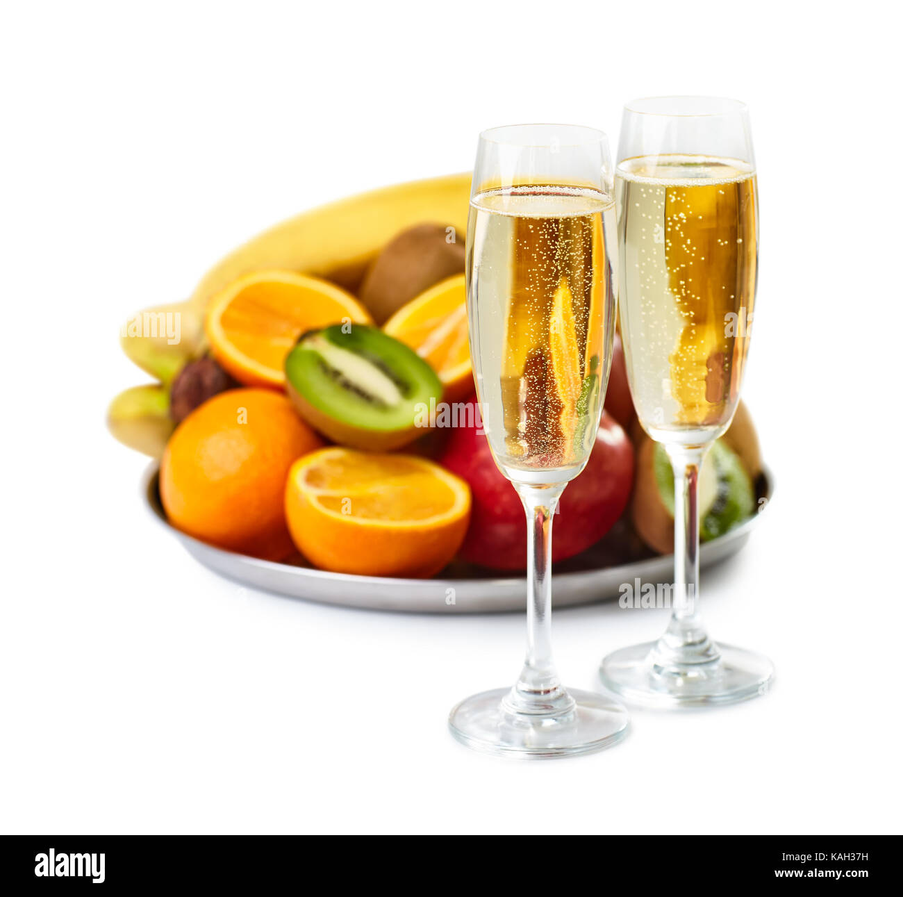 Two champagne glasses and ripe fruits plate isolated on white ...
