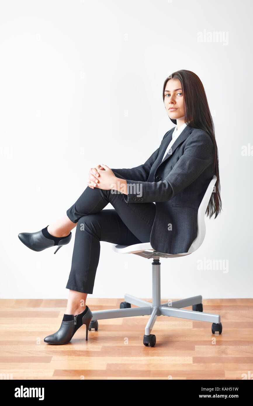 Portrait of young business woman sitting on chair in the office Stock ...