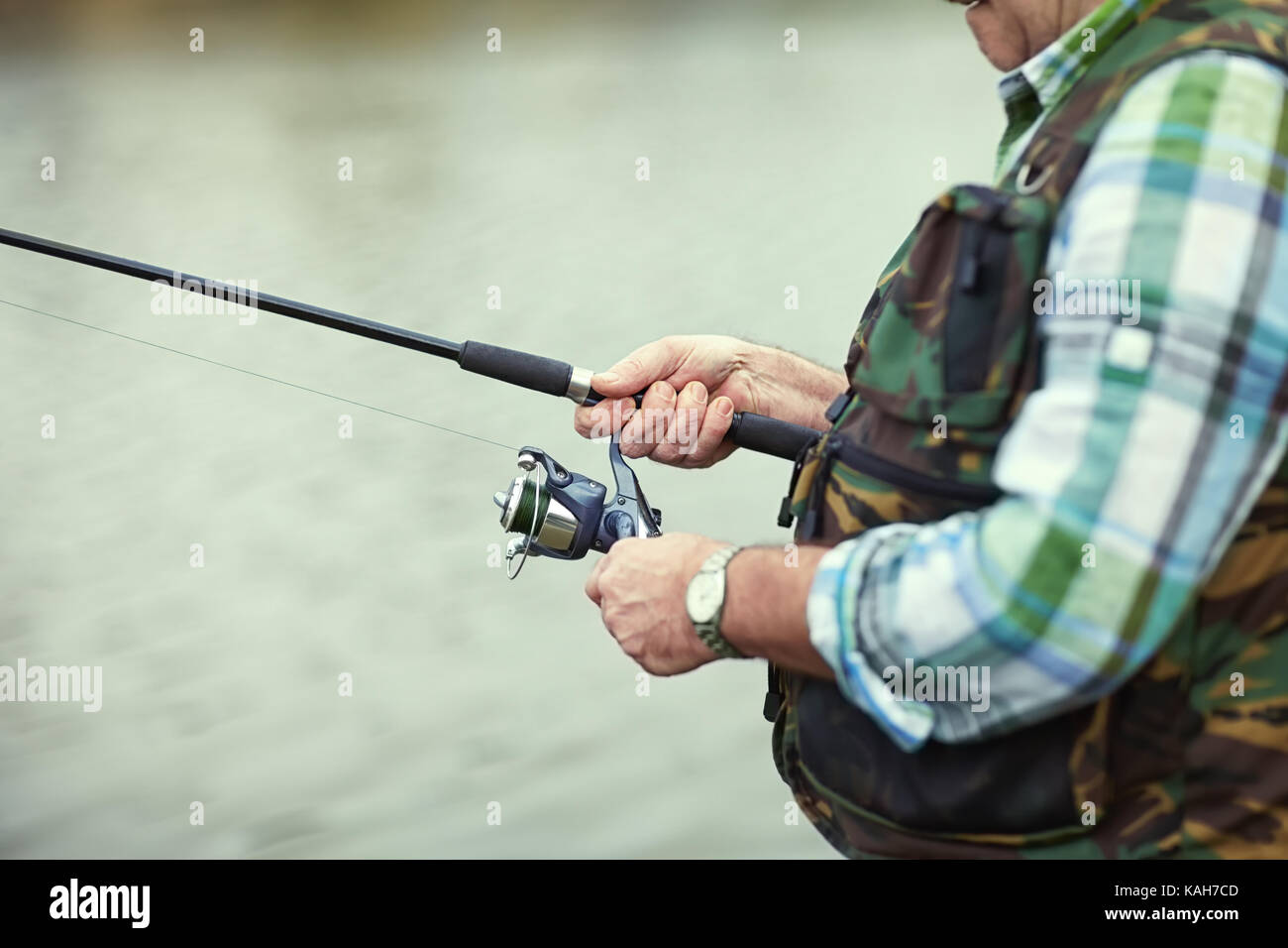 Fisherman`s hand holding fishing rod with reel Stock Photo - Alamy