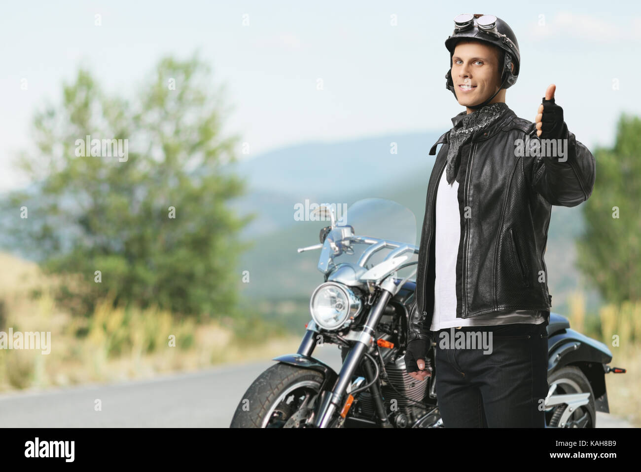Biker making a thumb up gesture in front of a motorcycle outdoors Stock ...