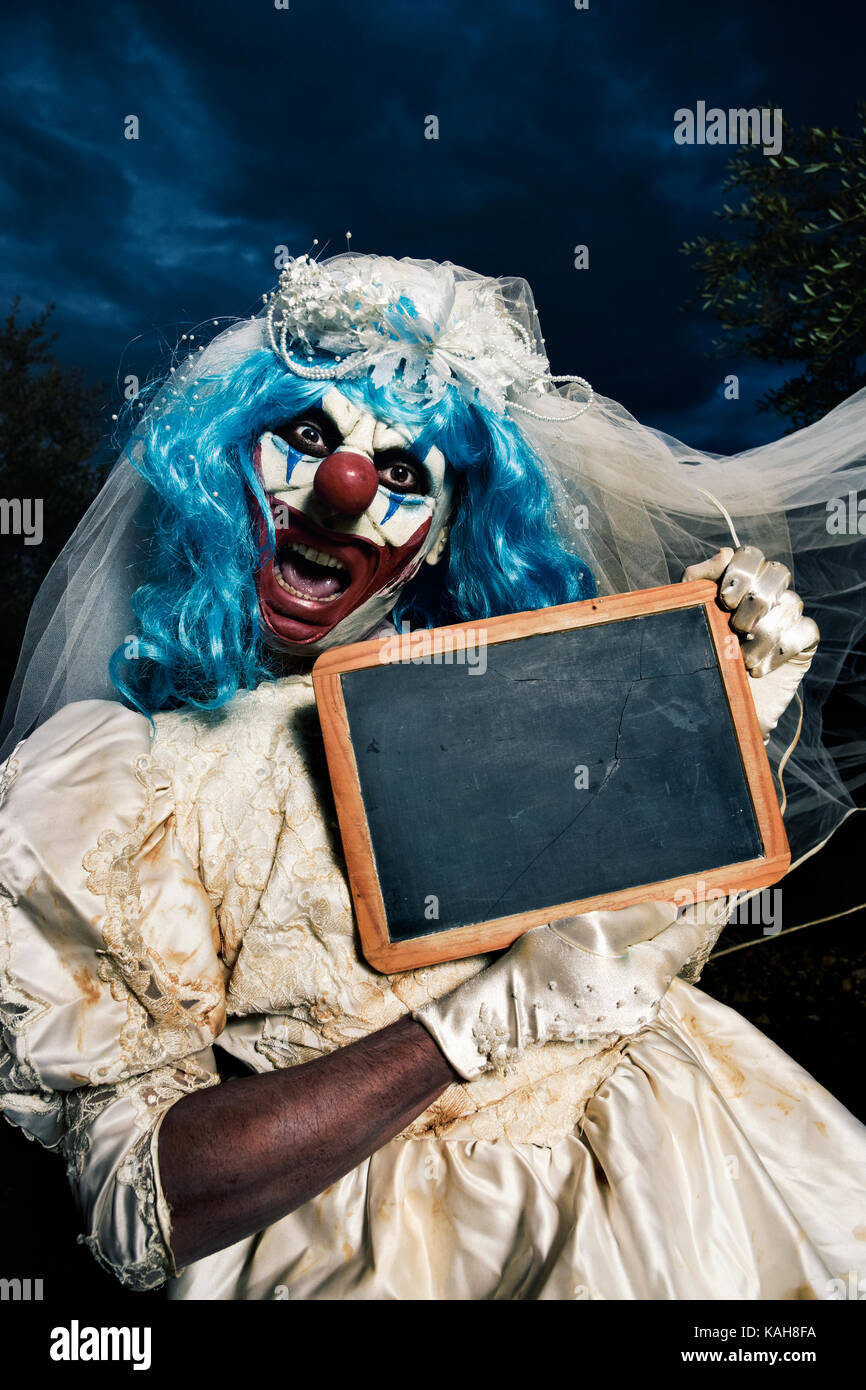 closeup of a scary evil clown wearing a dirty and ragged bride dress ...