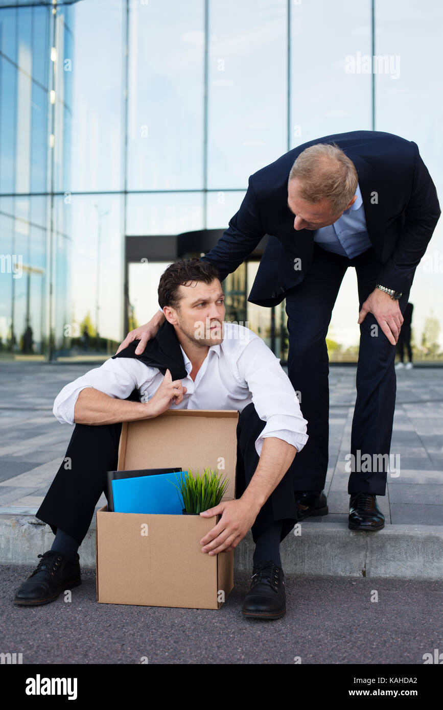 Fired business man sitting frustrated and upset on the street near ...