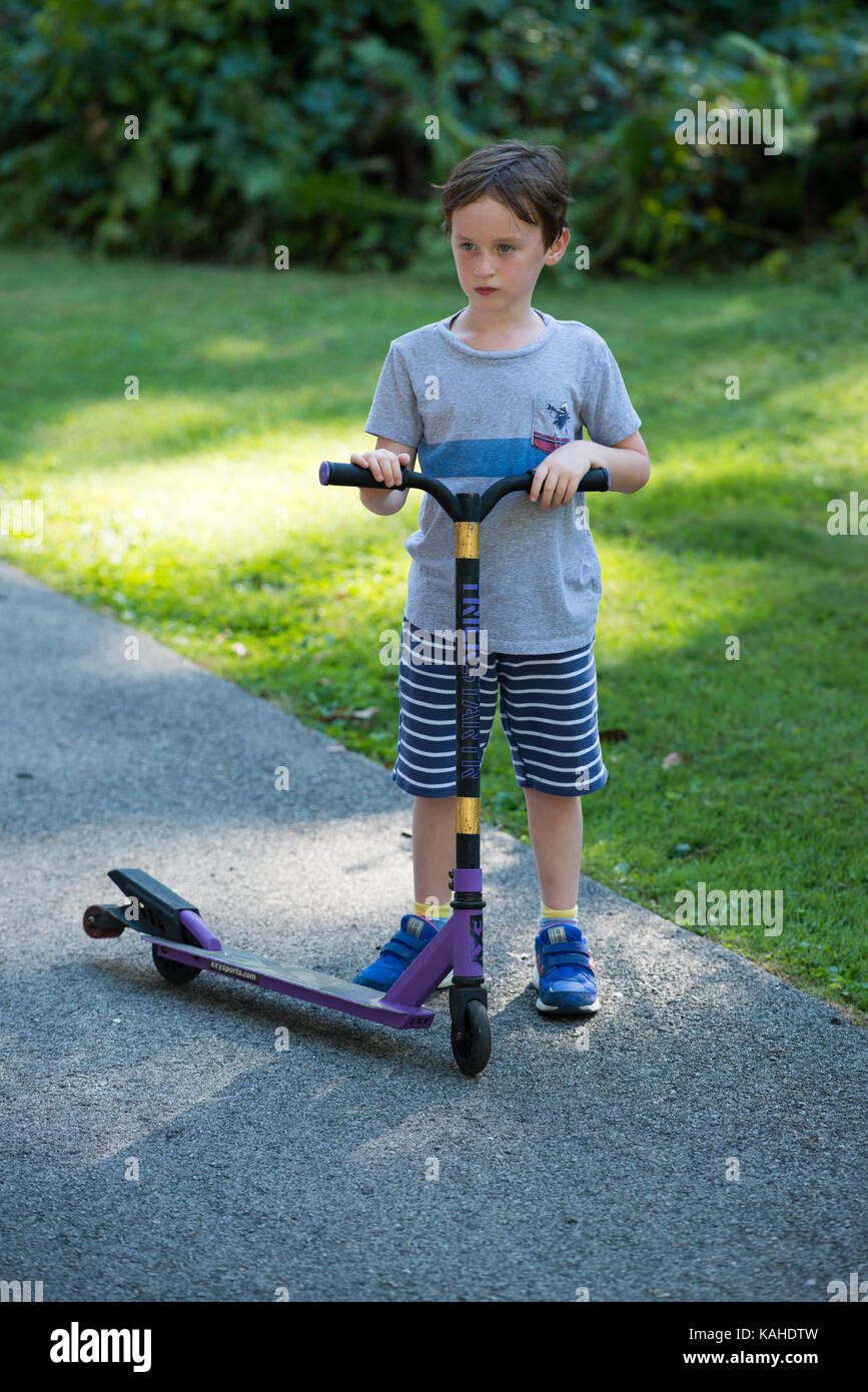 Young litte boy outside riding his scooter in the driveway Stock Photo ...