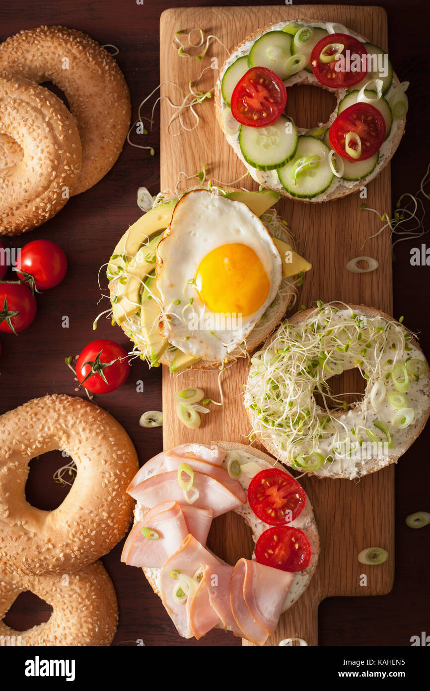 variety of sandwiches on bagels: egg, avocado, ham, tomato, soft cheese ...