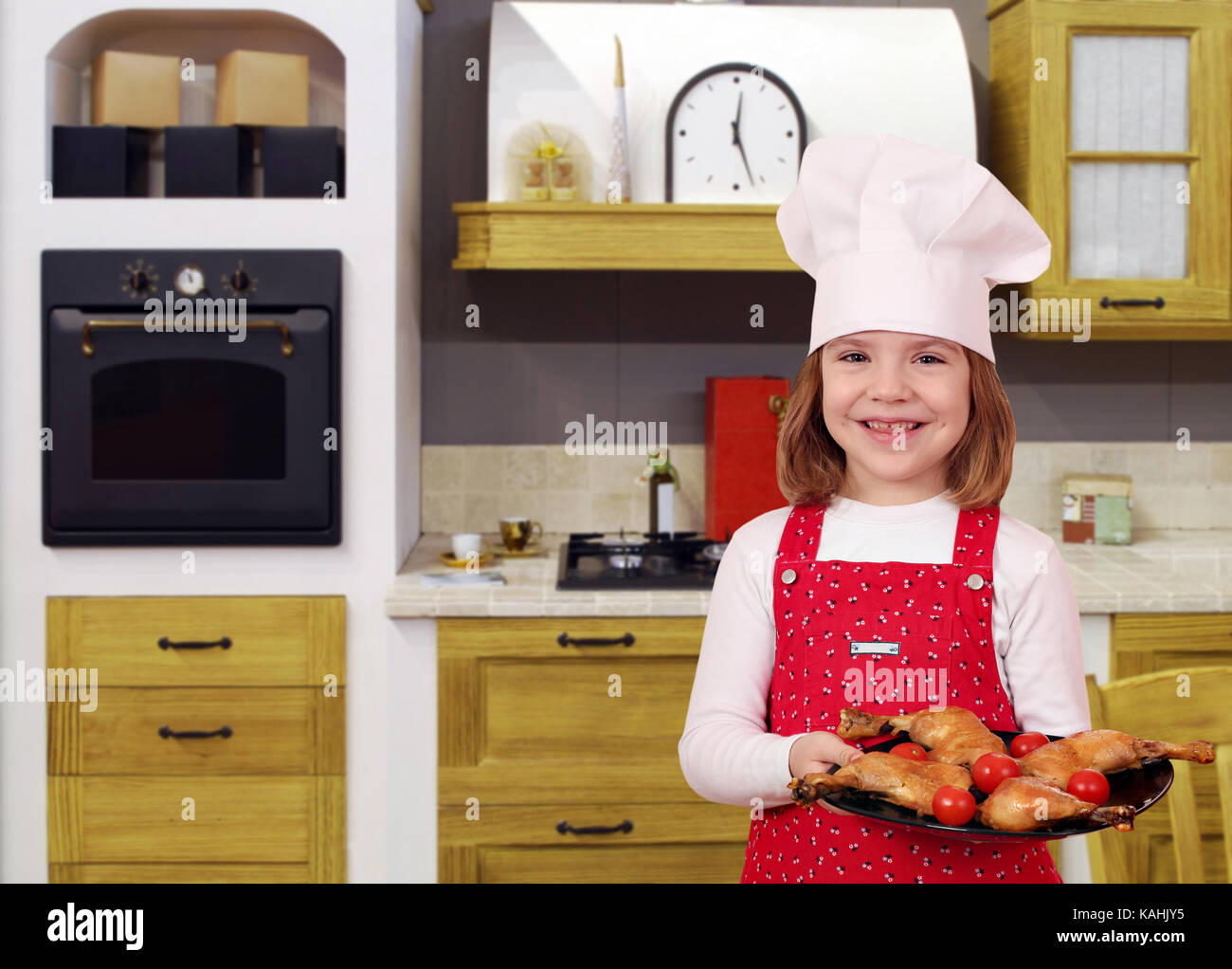 happy little girl cook with delicious chicken drumstick in kitchen ...