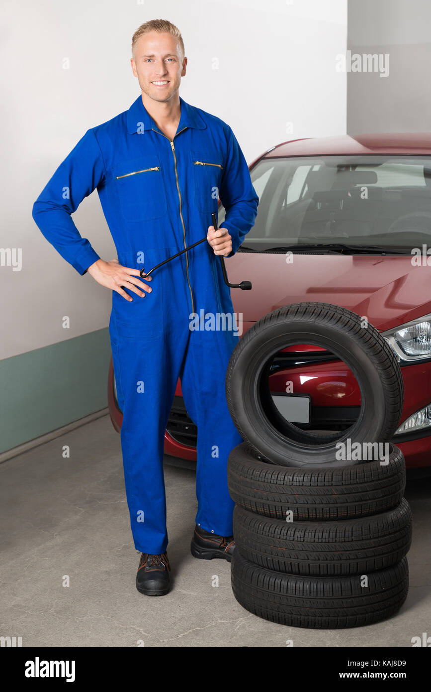 Happy Mechanic Holding Wrench Standing Besides Stack Of Tires Stock ...