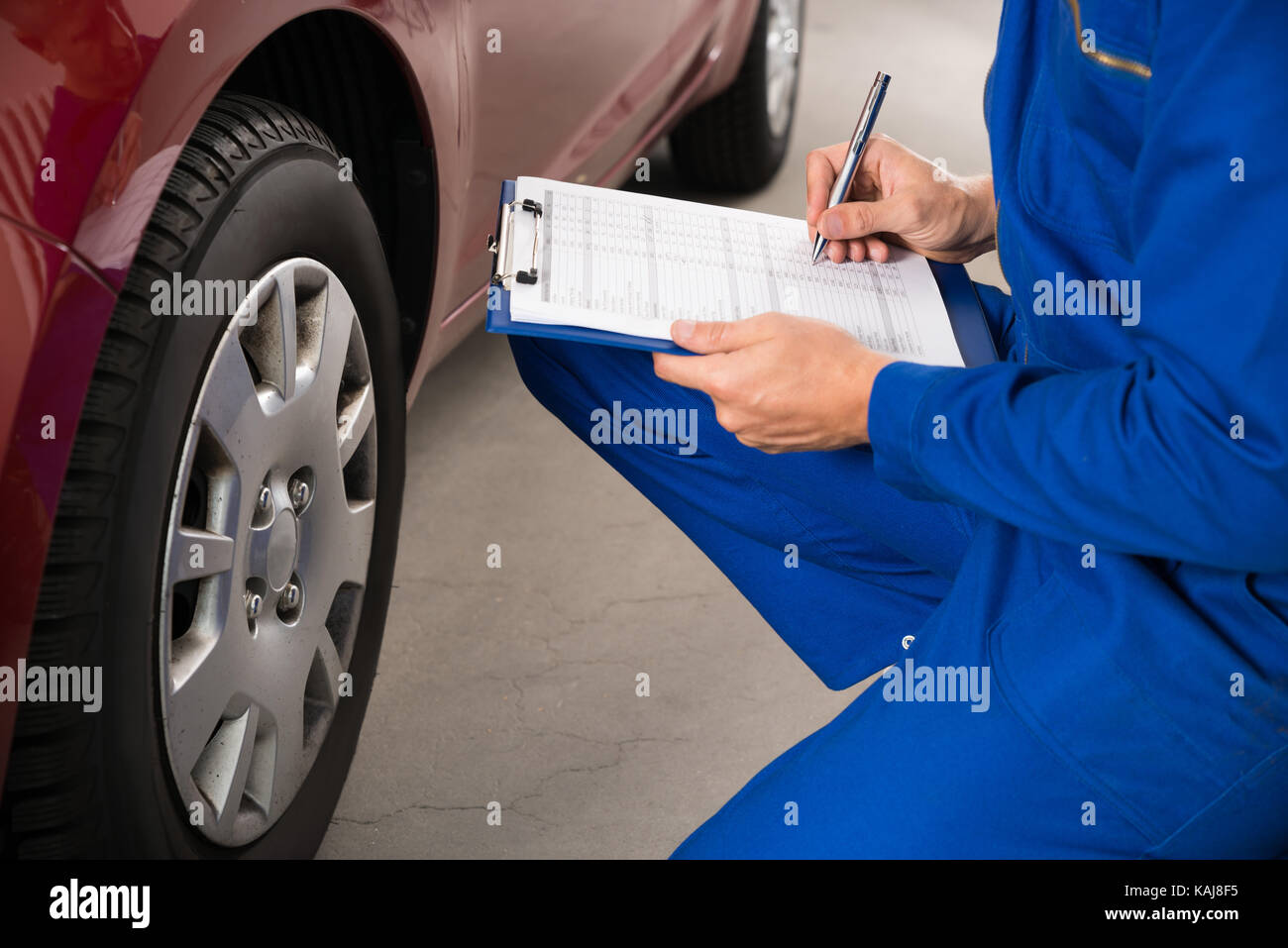 Young Mechanic Writing On Clipboard White Examining Car Wheel Stock ...