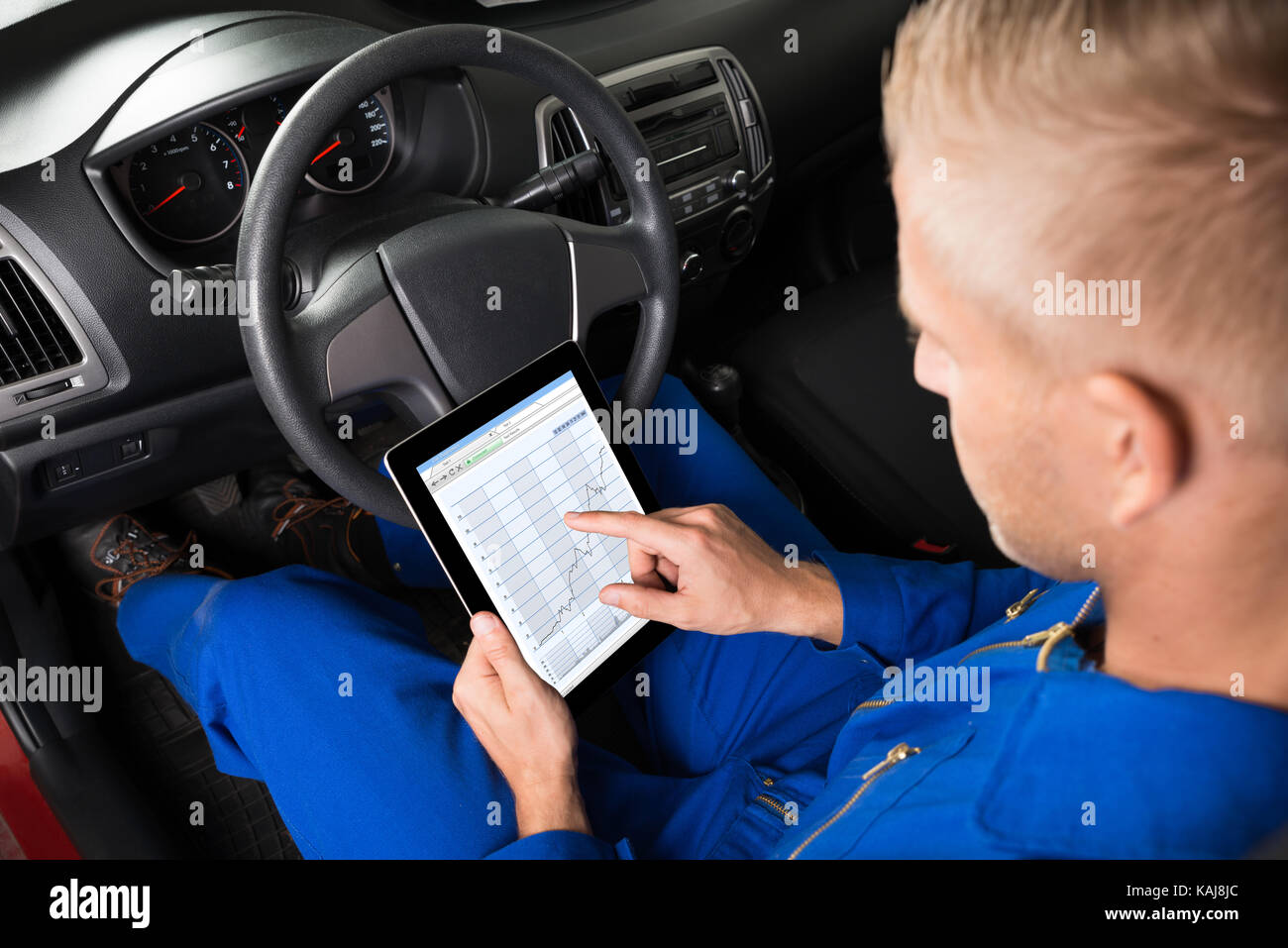 Mechanic Sitting In Car Looking At Graph On Digital Tablet Stock Photo ...