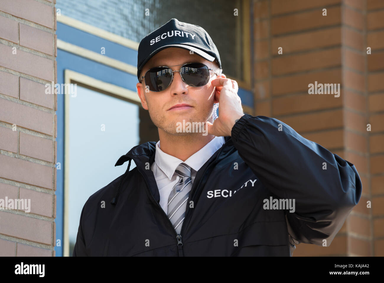Close-up Of Security Guard Standing In Front Of The Entrance Listening ...