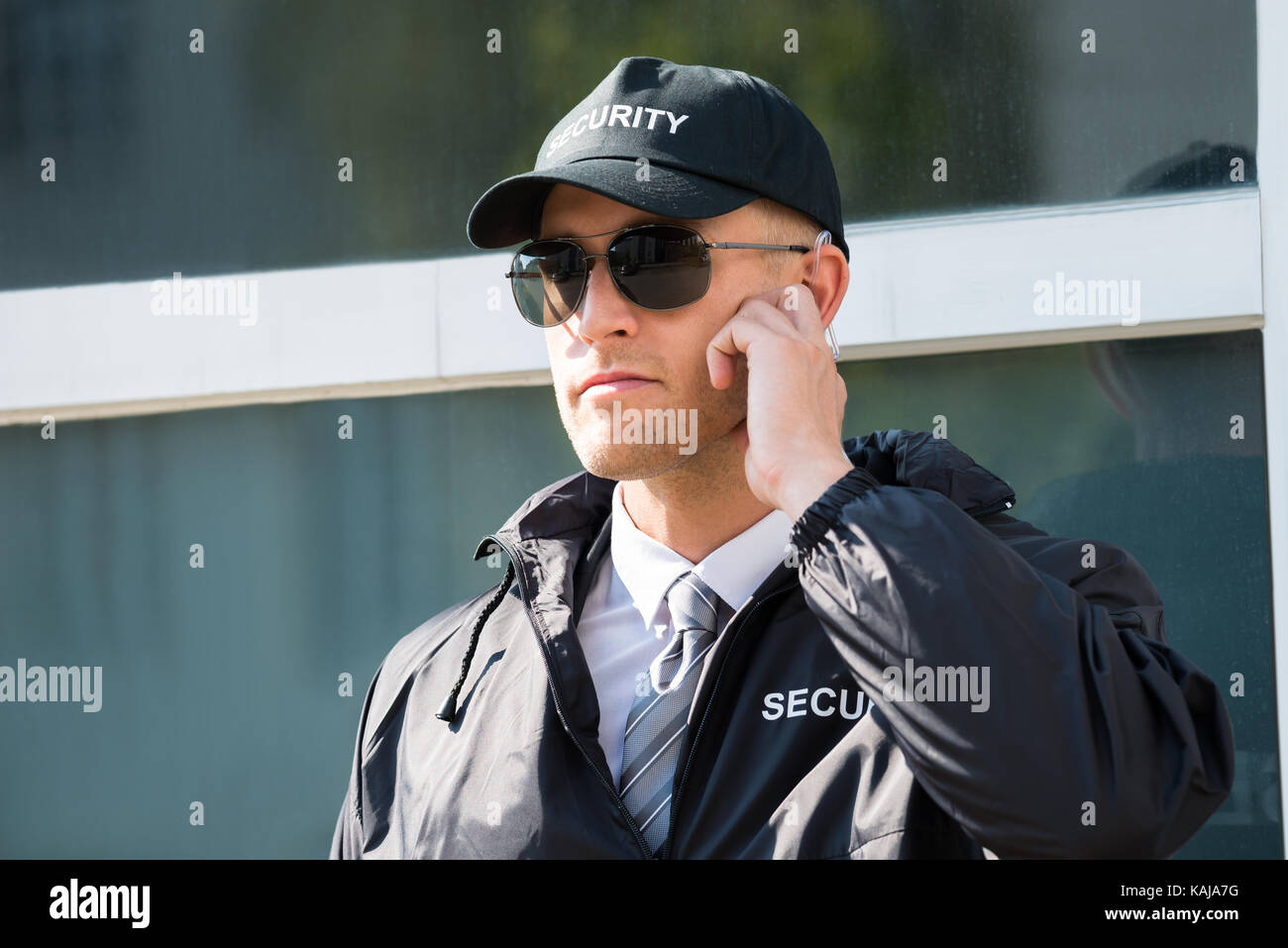 Close-up Of Security Guard Standing In Front Of The Entrance Listening ...